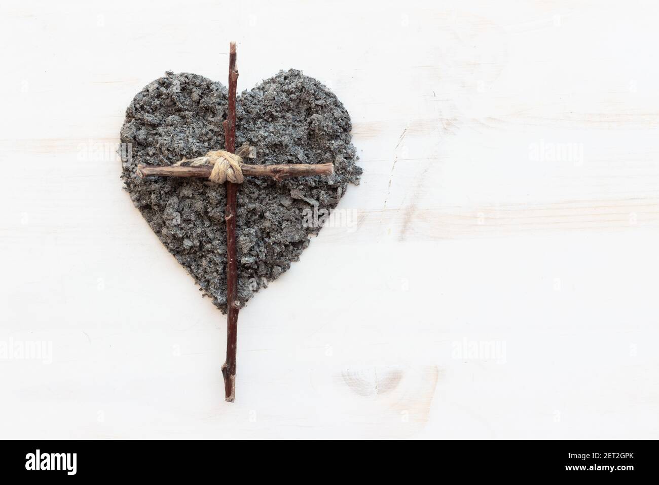 Simple wood christian cross and a heart of ashes on a white wood ...