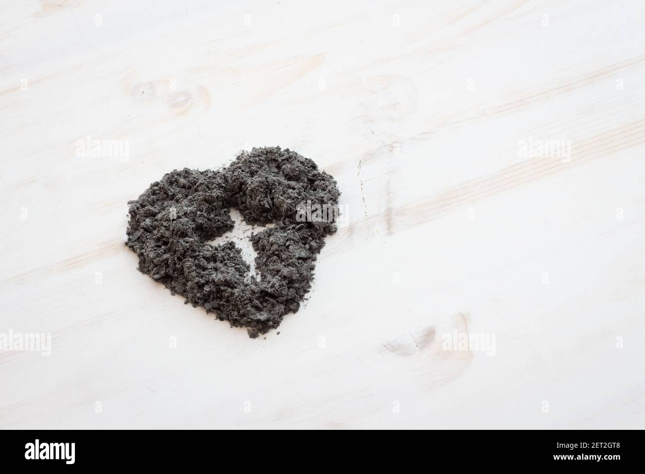 shape of a christian cross in a heart of ash on a white wood background ...