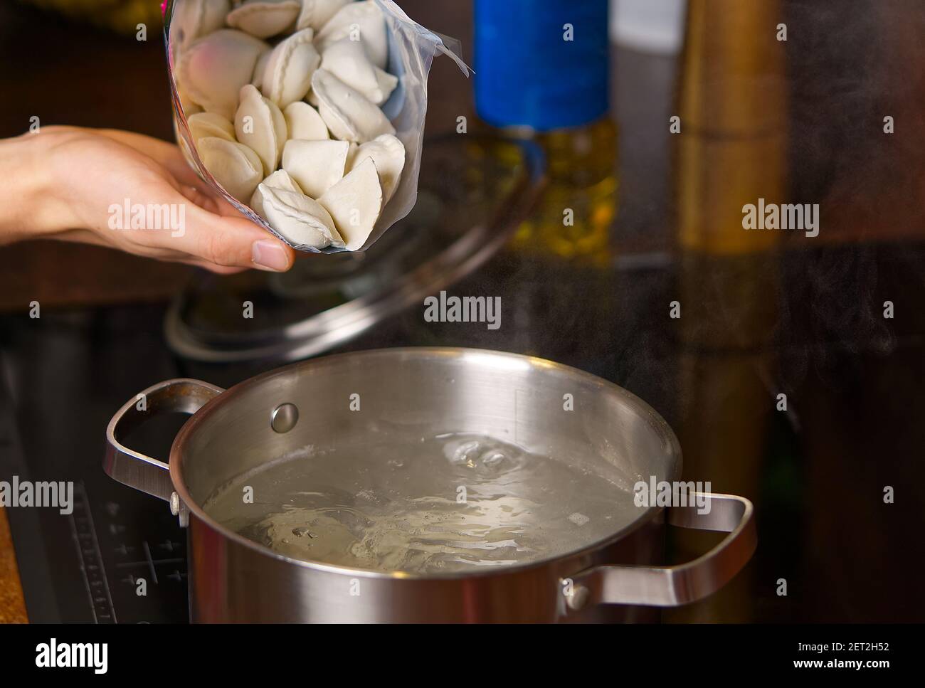 pouring dumplings from the packaging into pots of boiling water. Boiled ...