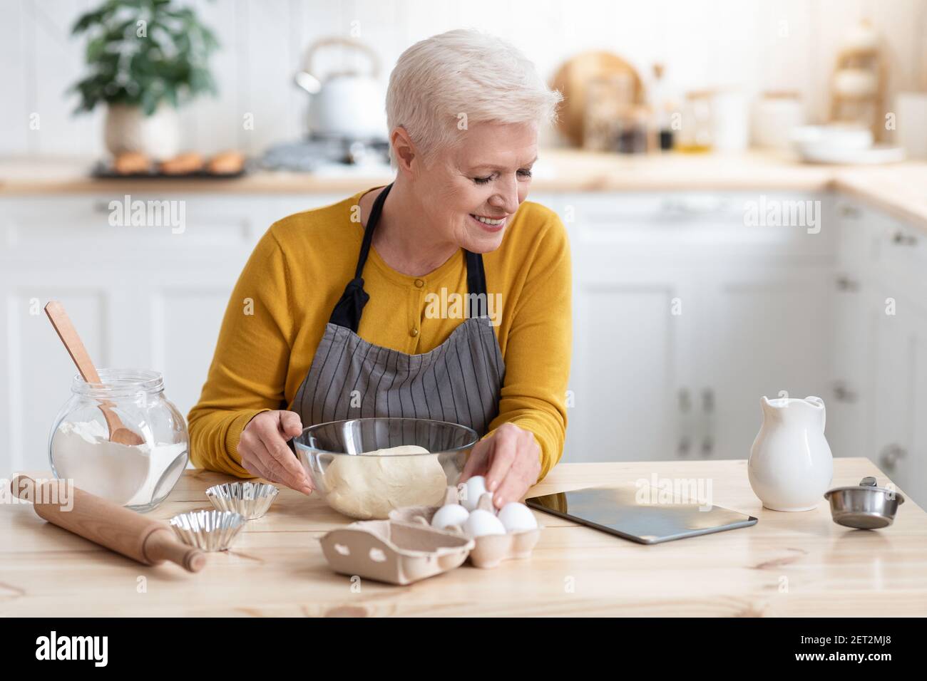 Happy old woman cooking by recipes from Internet Stock Photo - Alamy