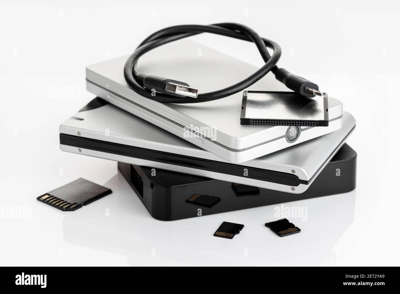 Group of external Hard disks and memory cards on white table. Data ...