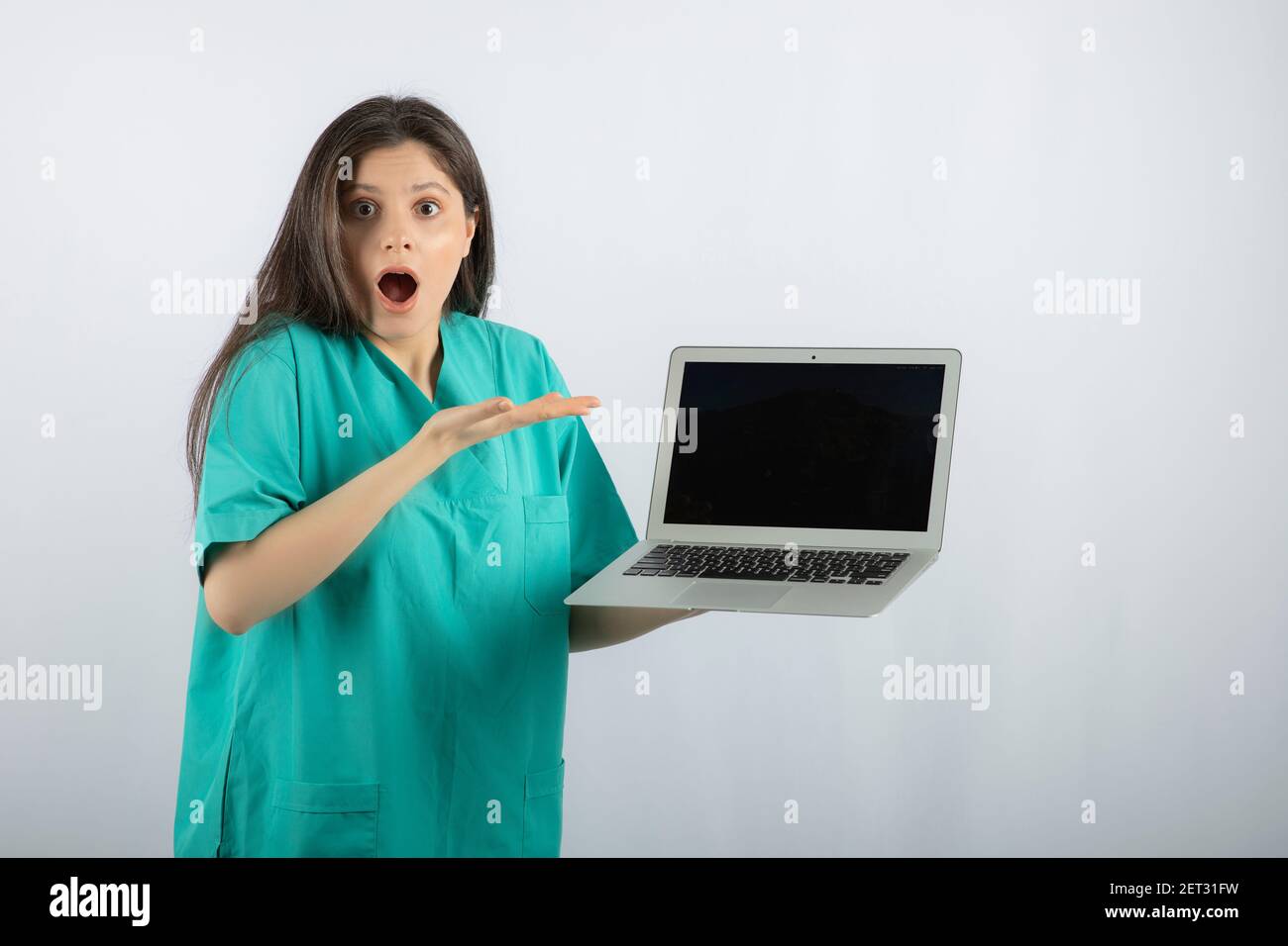 Young female nurse with laptop surprised about something on white ...