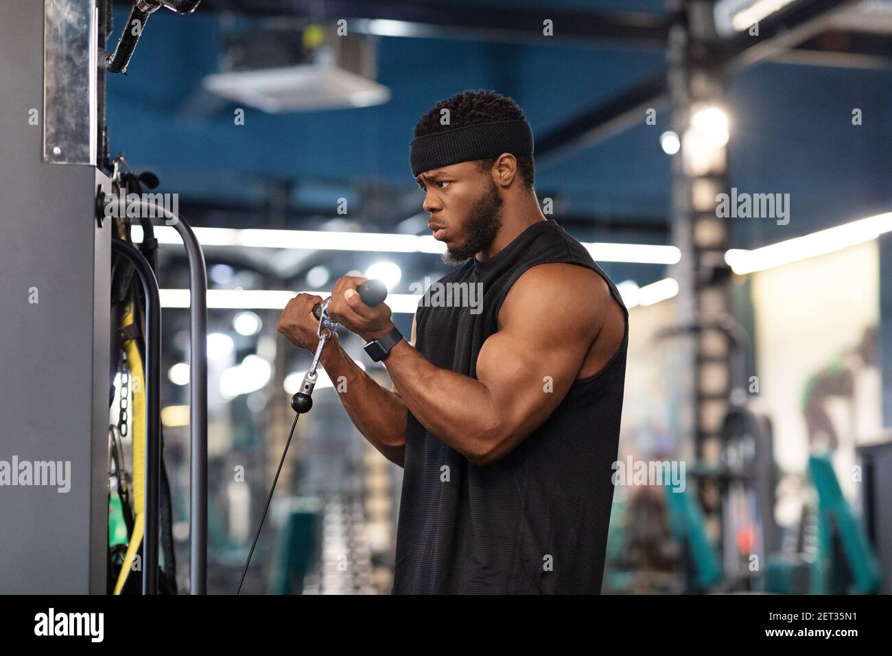 Concentrated black sportsman training muscles on block exerciser in gym ...