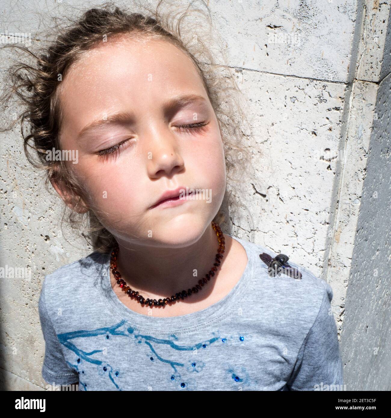 Girl standing in the sun with an insect on her shoulder Stock Photo - Alamy