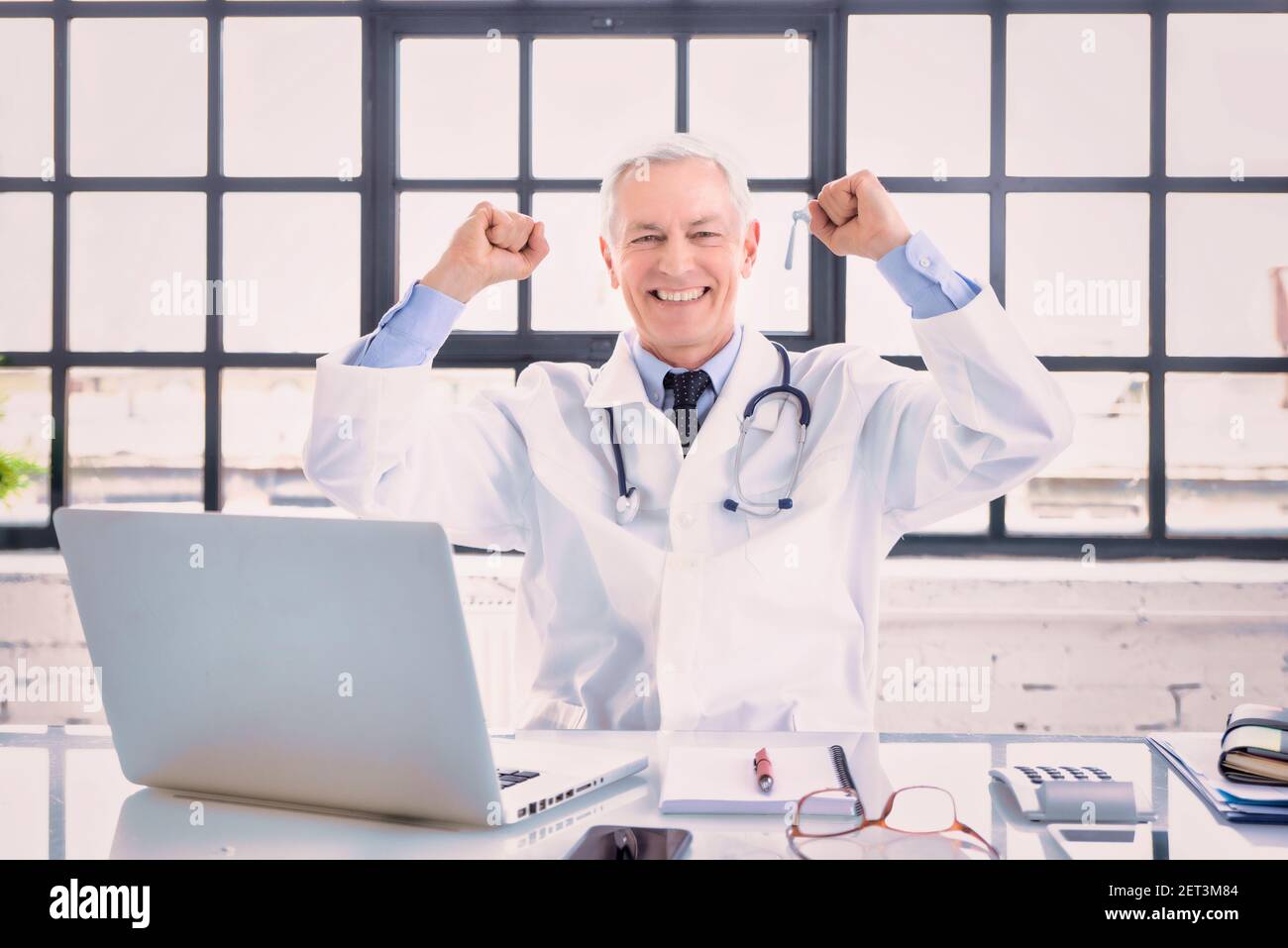 Shot of successful male doctor celebrating his success while sitting in ...