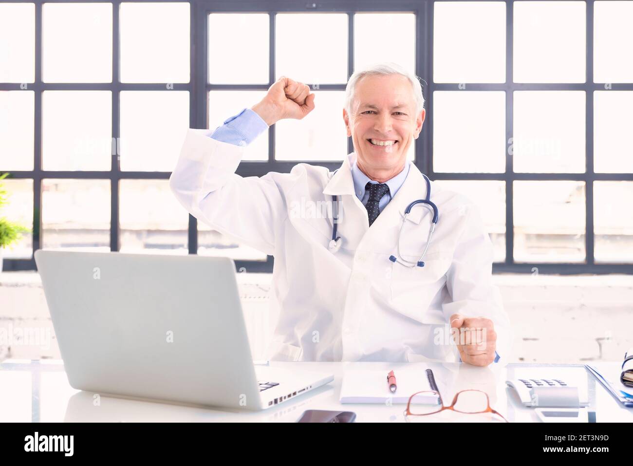 Shot of successful male doctor celebrating his success while sitting in ...