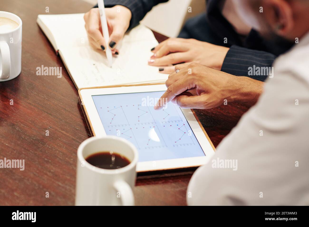 Business people pointing at line chart Stock Photo - Alamy