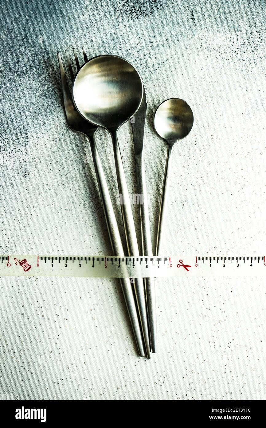 Overhead view of Cutlery and a tape measure for intermittent fasting ...