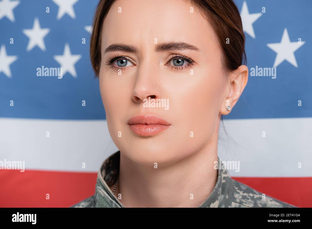 Soldier looking away near american flag blurred at background Stock ...