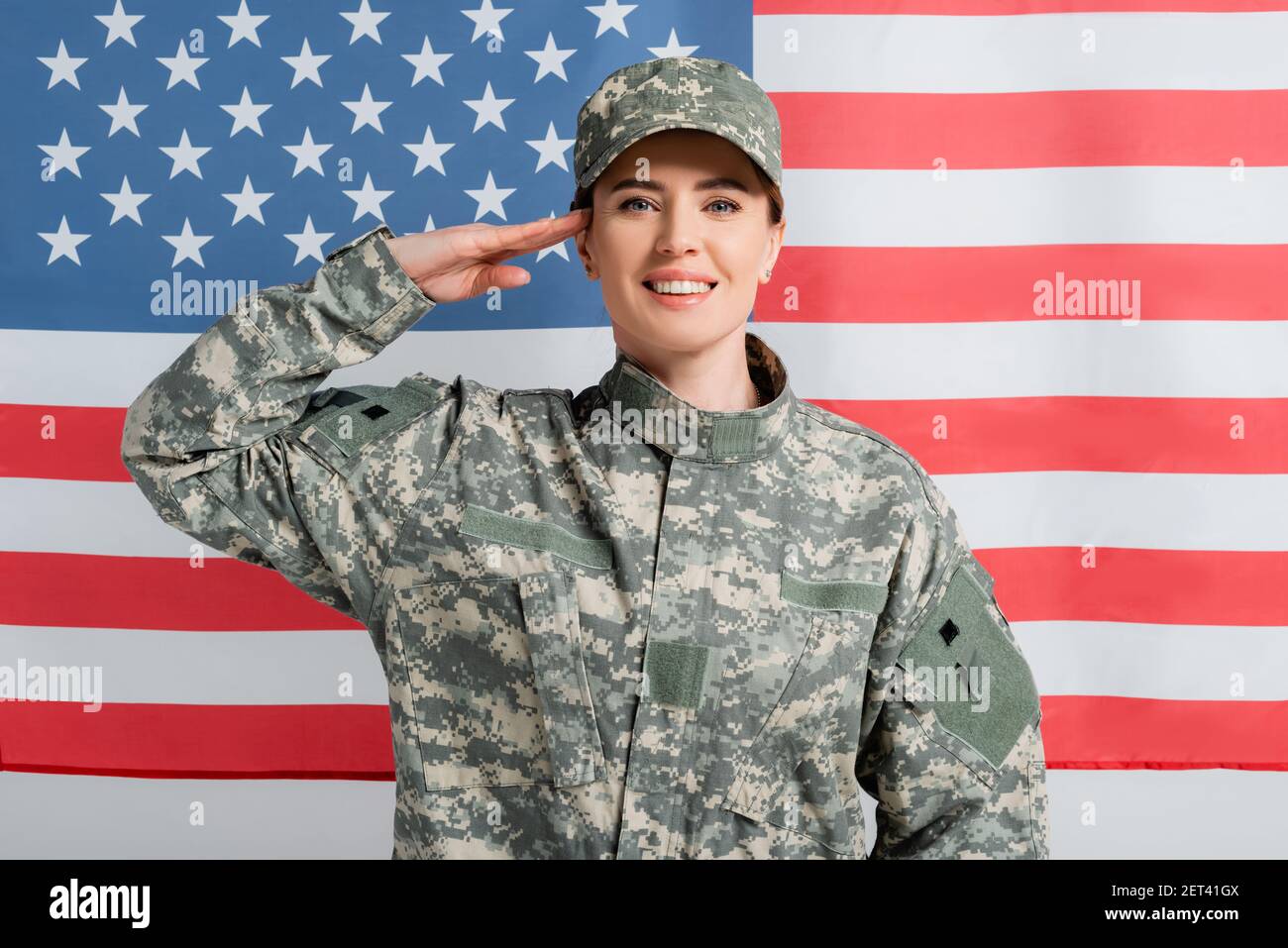 Smiling soldier saluting near american flag at background Stock Photo ...
