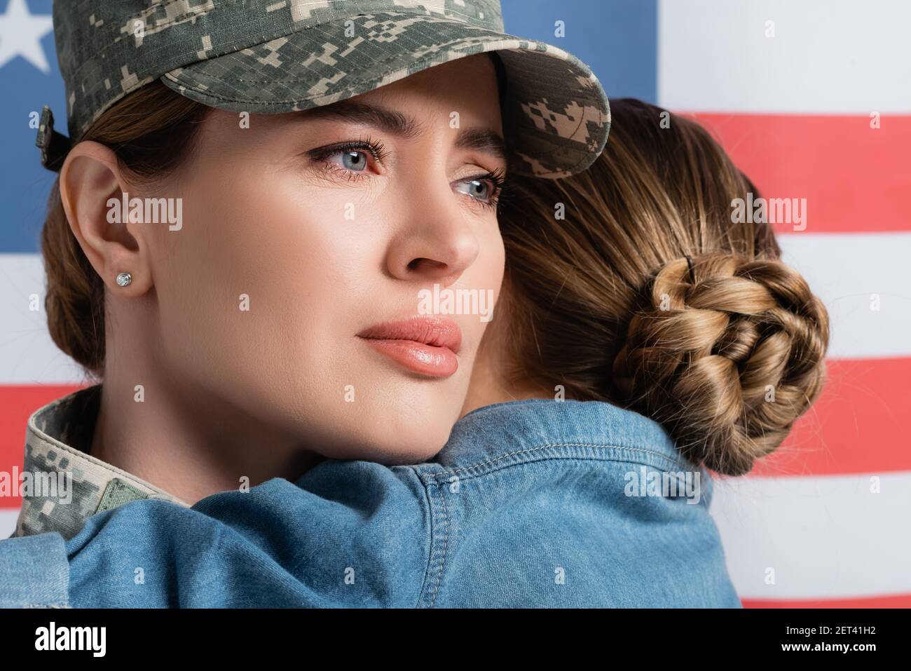 Woman in military uniform standing near daughter and american flag at ...