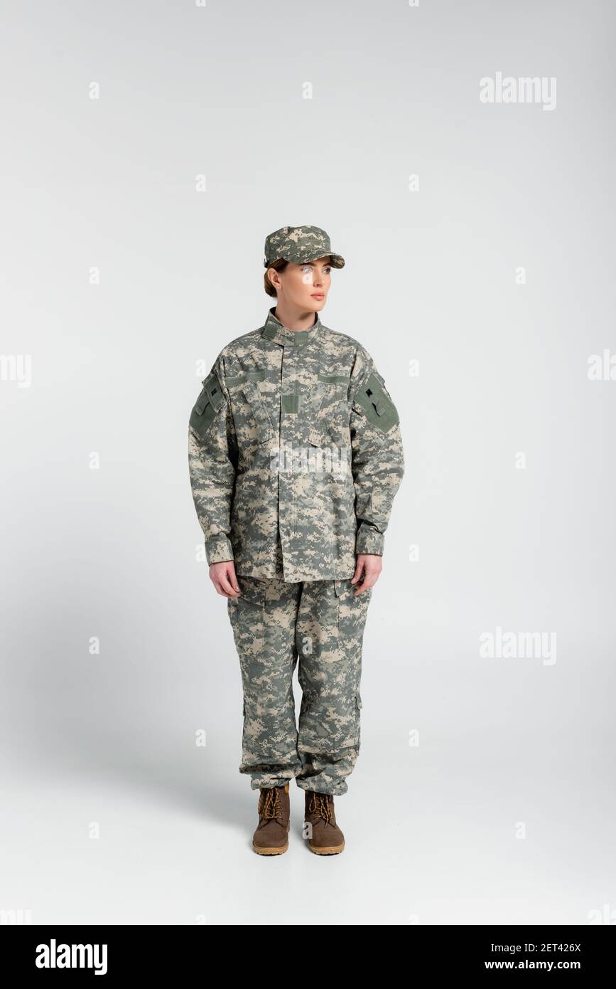 Full length of soldier in military uniform standing on grey background ...