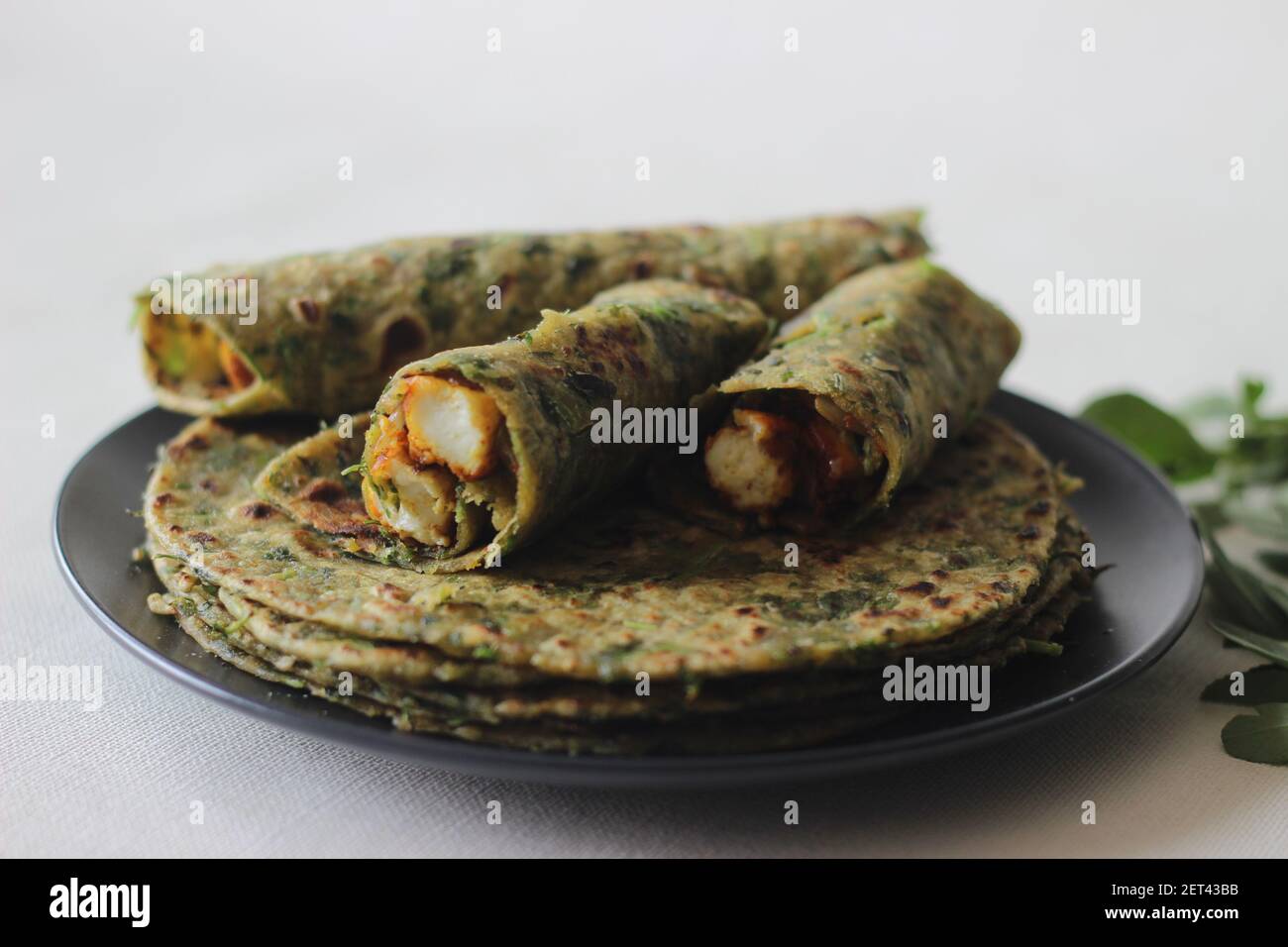 Whole wheat methi thepla rolls with paneer capsicum filling and a bowl ...