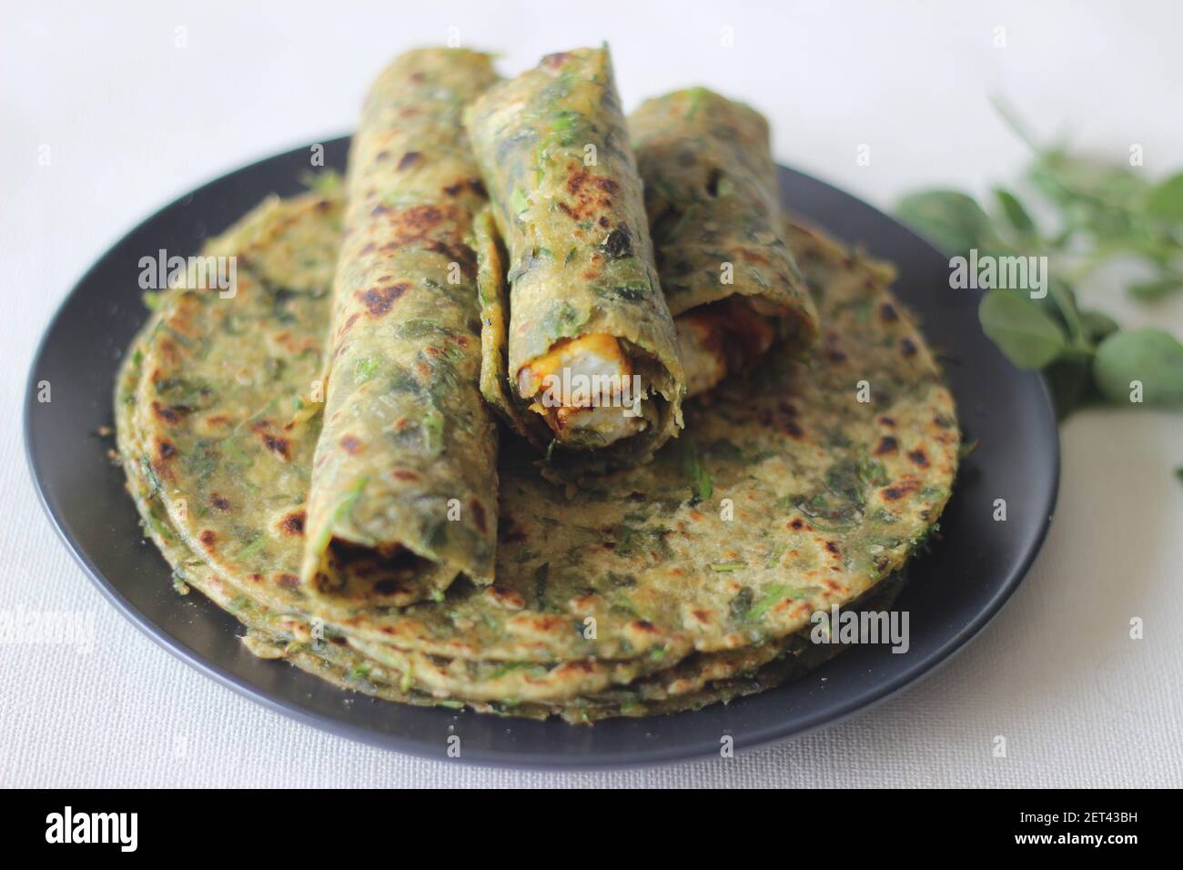 Whole wheat methi thepla rolls with paneer capsicum filling and a bowl ...