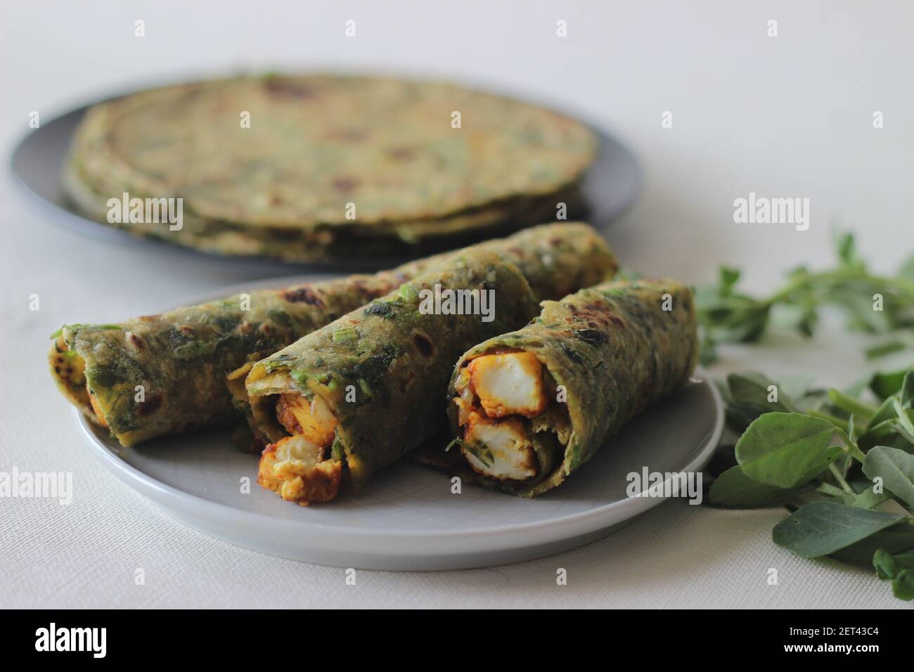 Whole wheat methi thepla rolls with paneer capsicum filling and a bowl ...