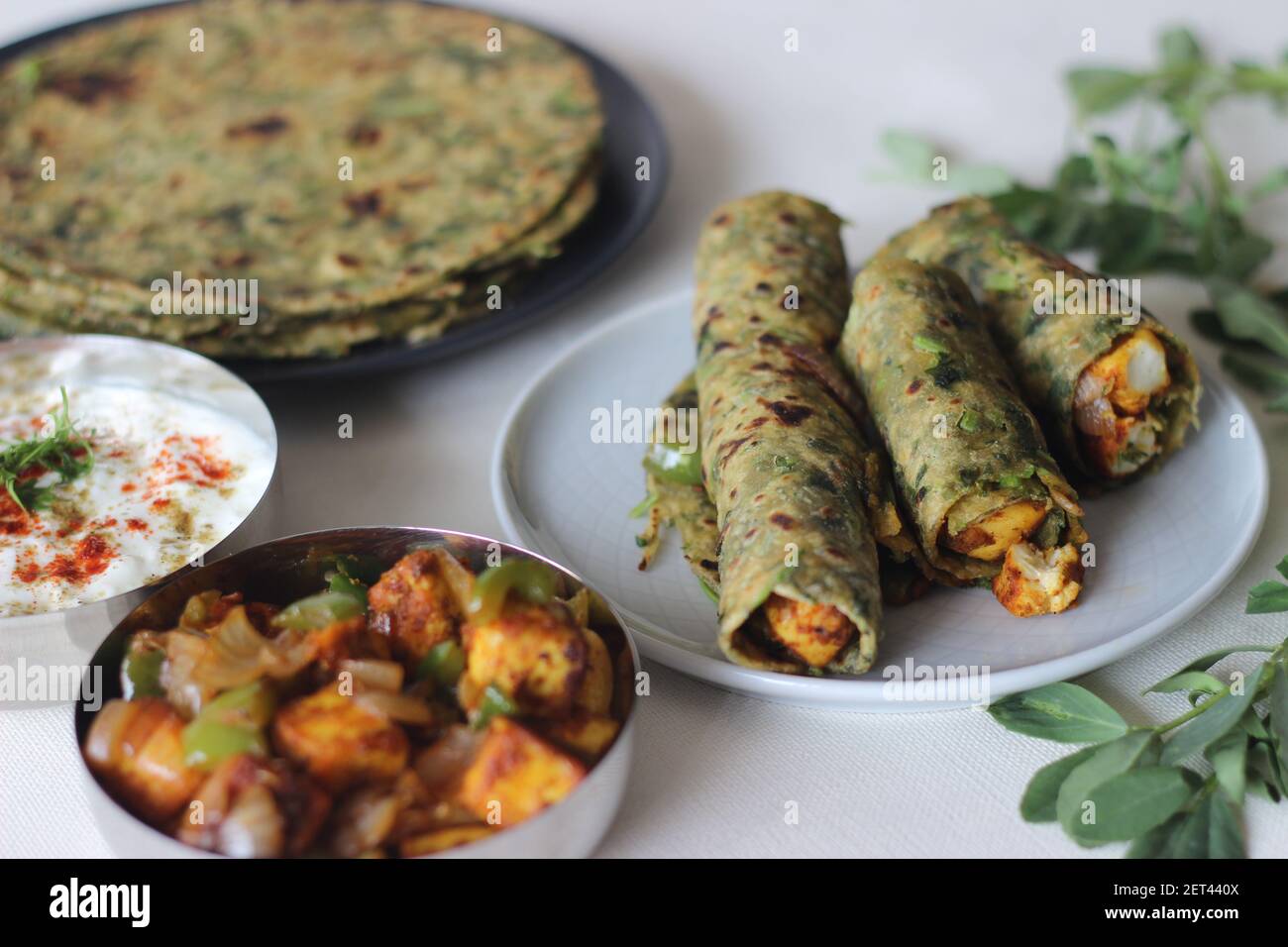 Whole wheat methi thepla rolls with paneer capsicum filling and a bowl ...