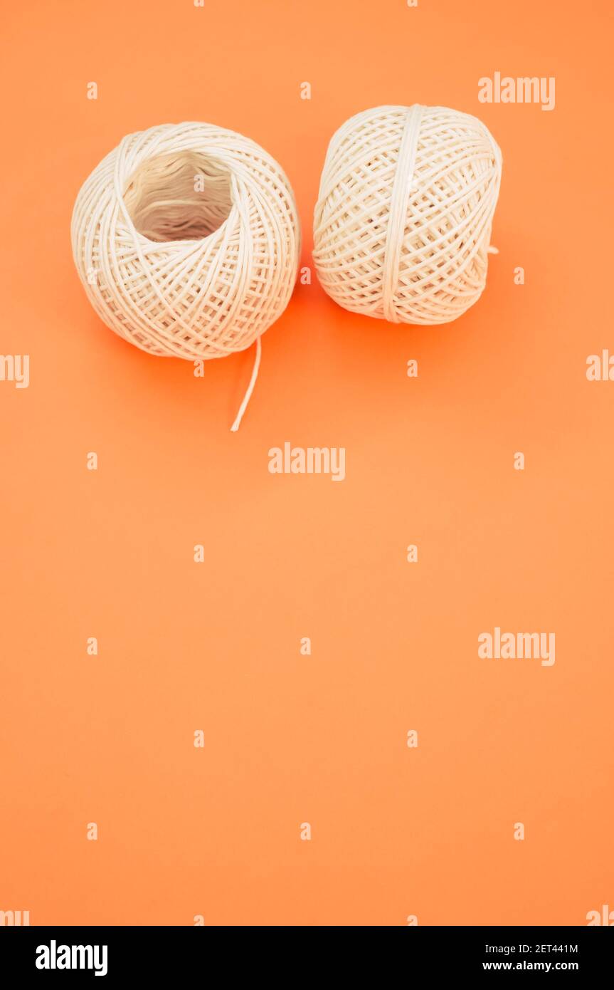 A vertical shot of two white balls of twine isolated on an orange ...