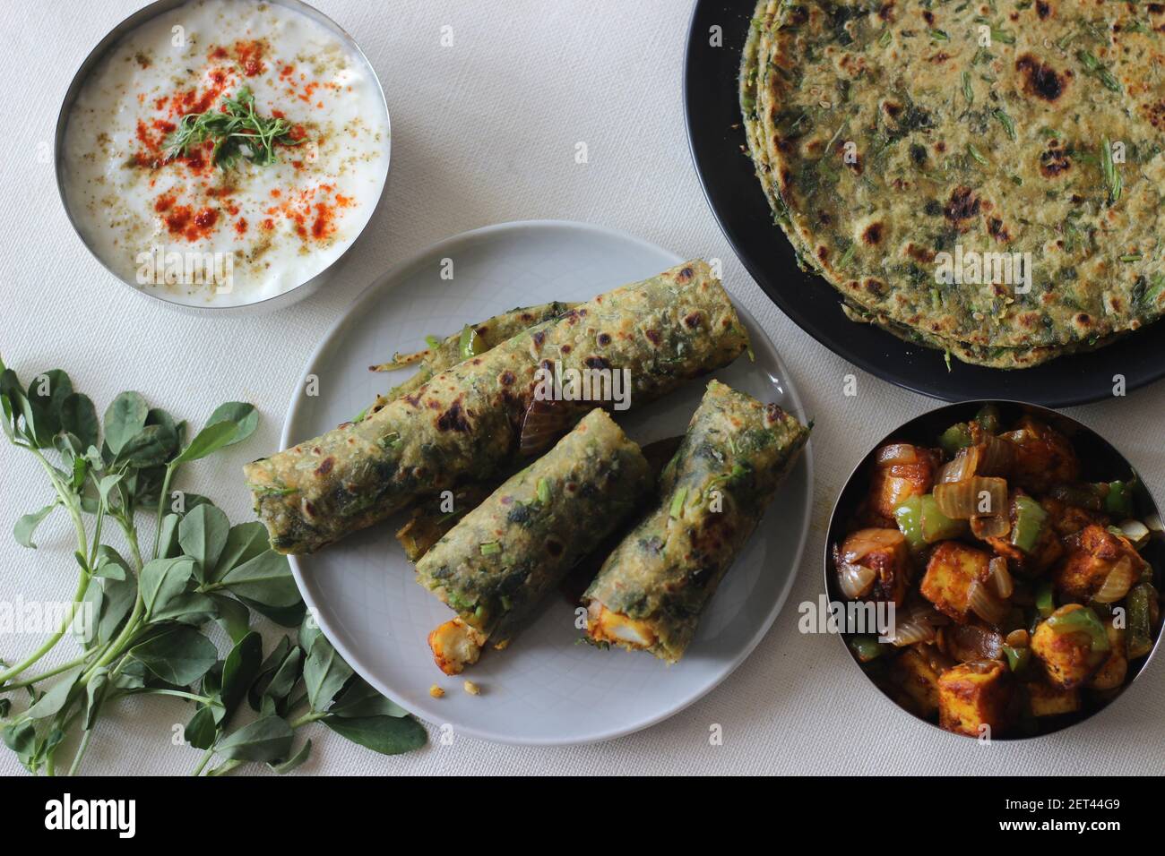 Whole wheat methi thepla rolls with paneer capsicum filling and a bowl ...