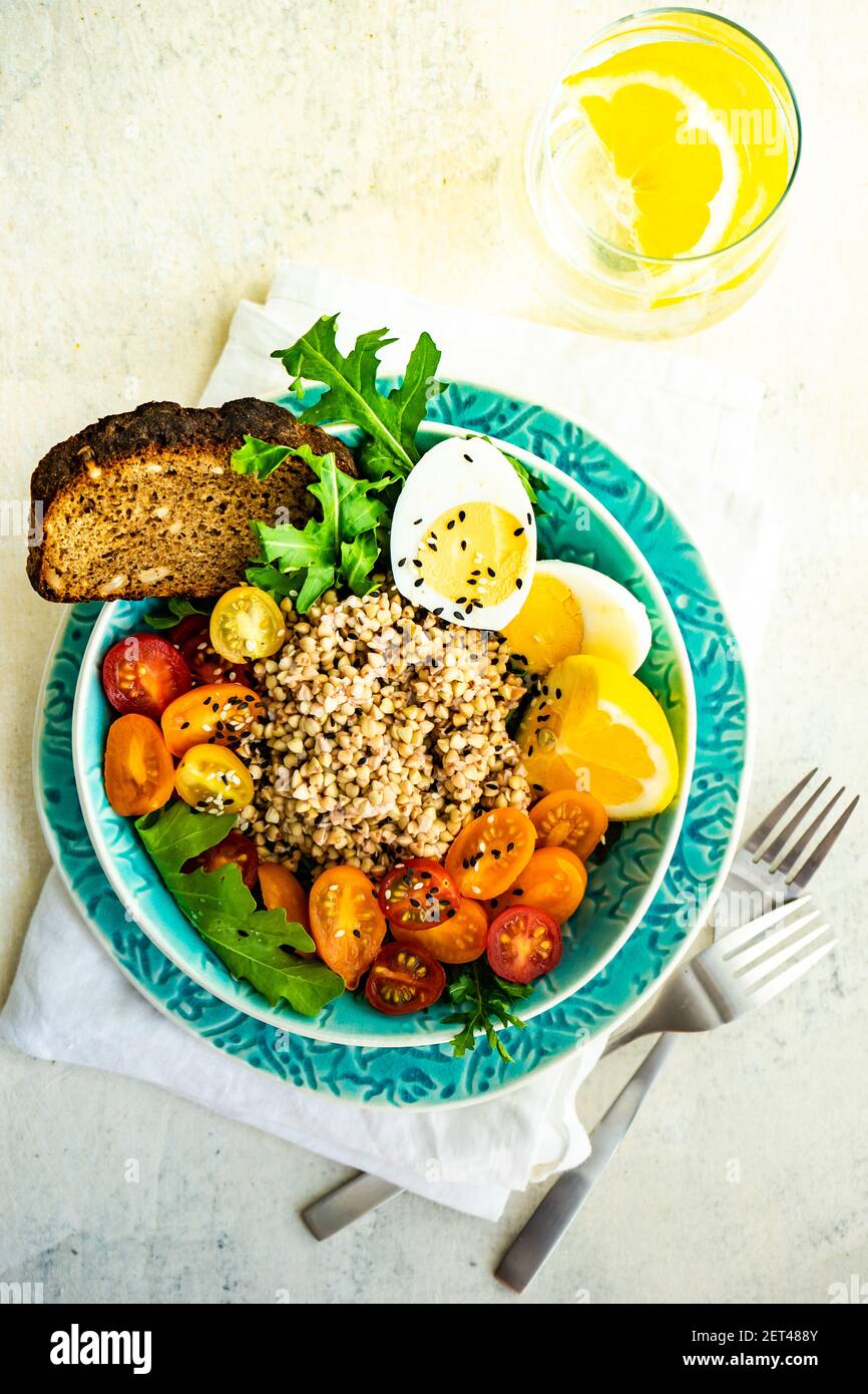 Bowl of buckwheat salad with rocket, tomato, lettuce, hard boiled egg ...