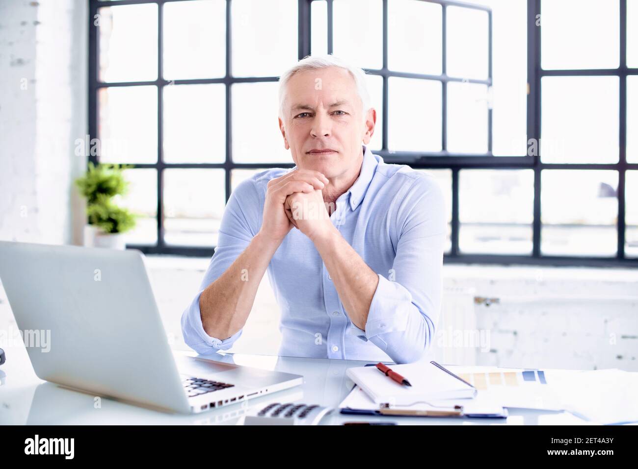 Shot of senior businessman sitting behind his laptop while working at ...