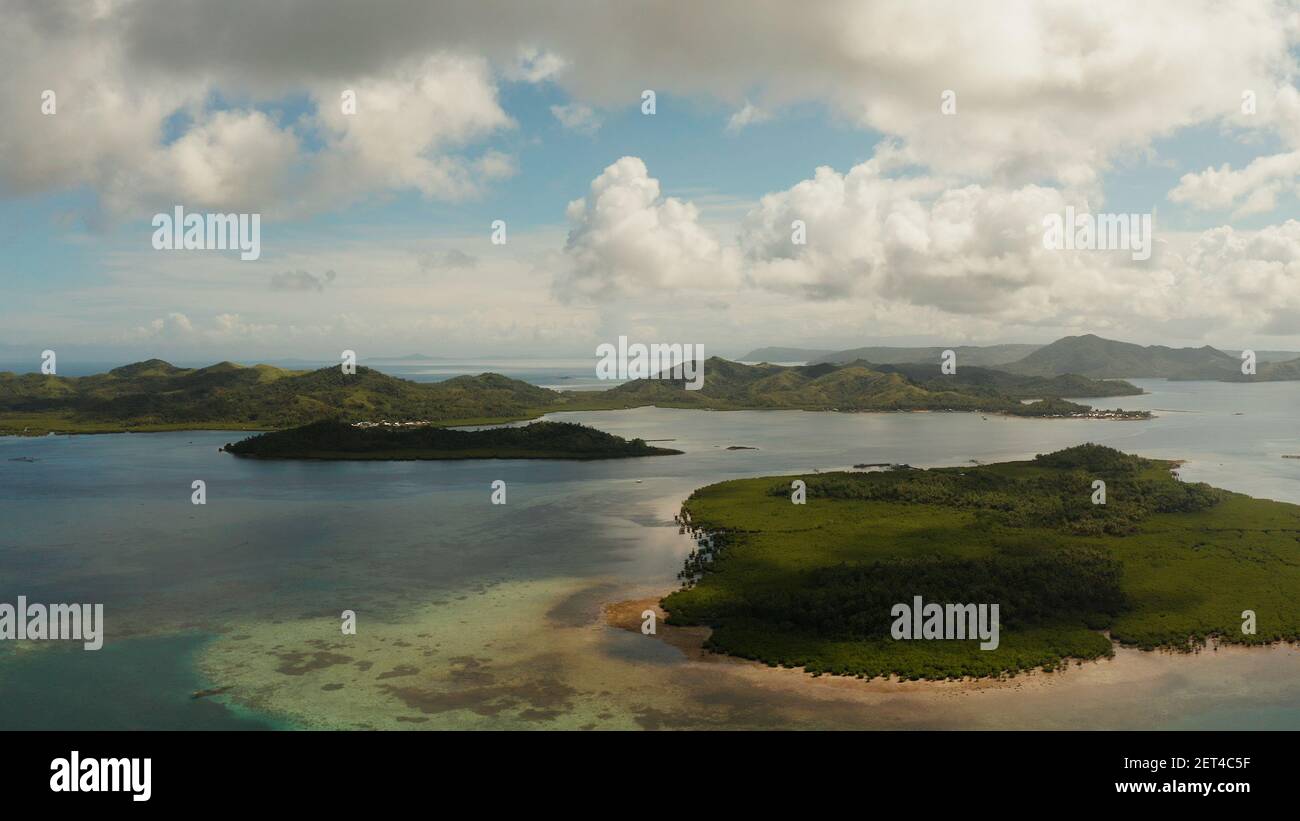 Tropical island covered with forest surrounded by an atoll and a coral ...