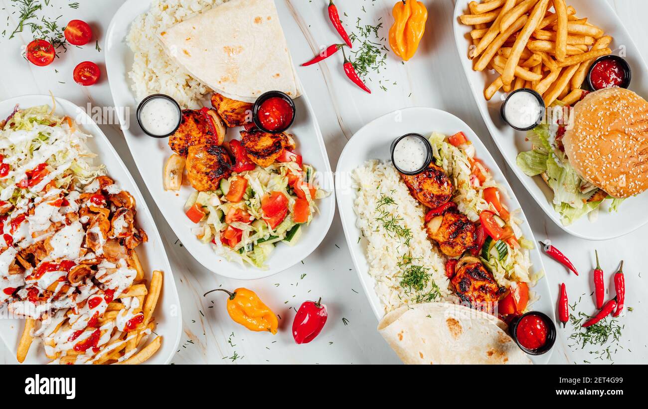 A top view of many dishes on a white table with chili peppers and herbs ...