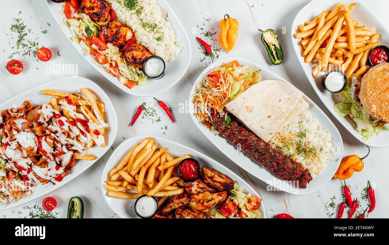 A top view of many dishes on a white table with chili peppers and herbs ...