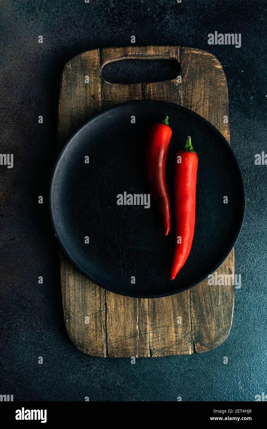 Two red chilli peppers on a black plate Stock Photo - Alamy