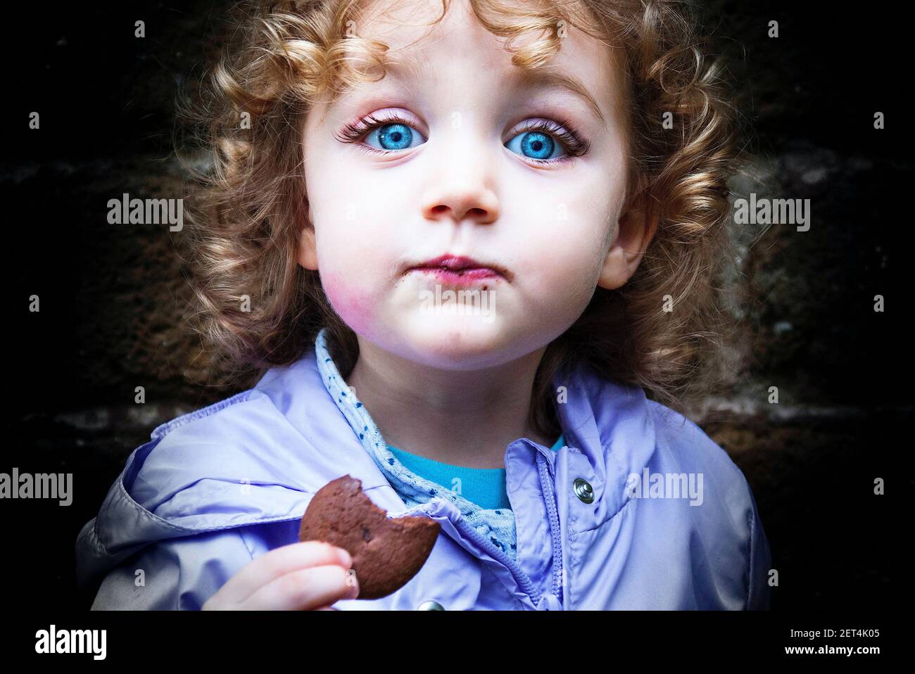 Portrait of a girl eating a chocolate cookie Stock Photo - Alamy
