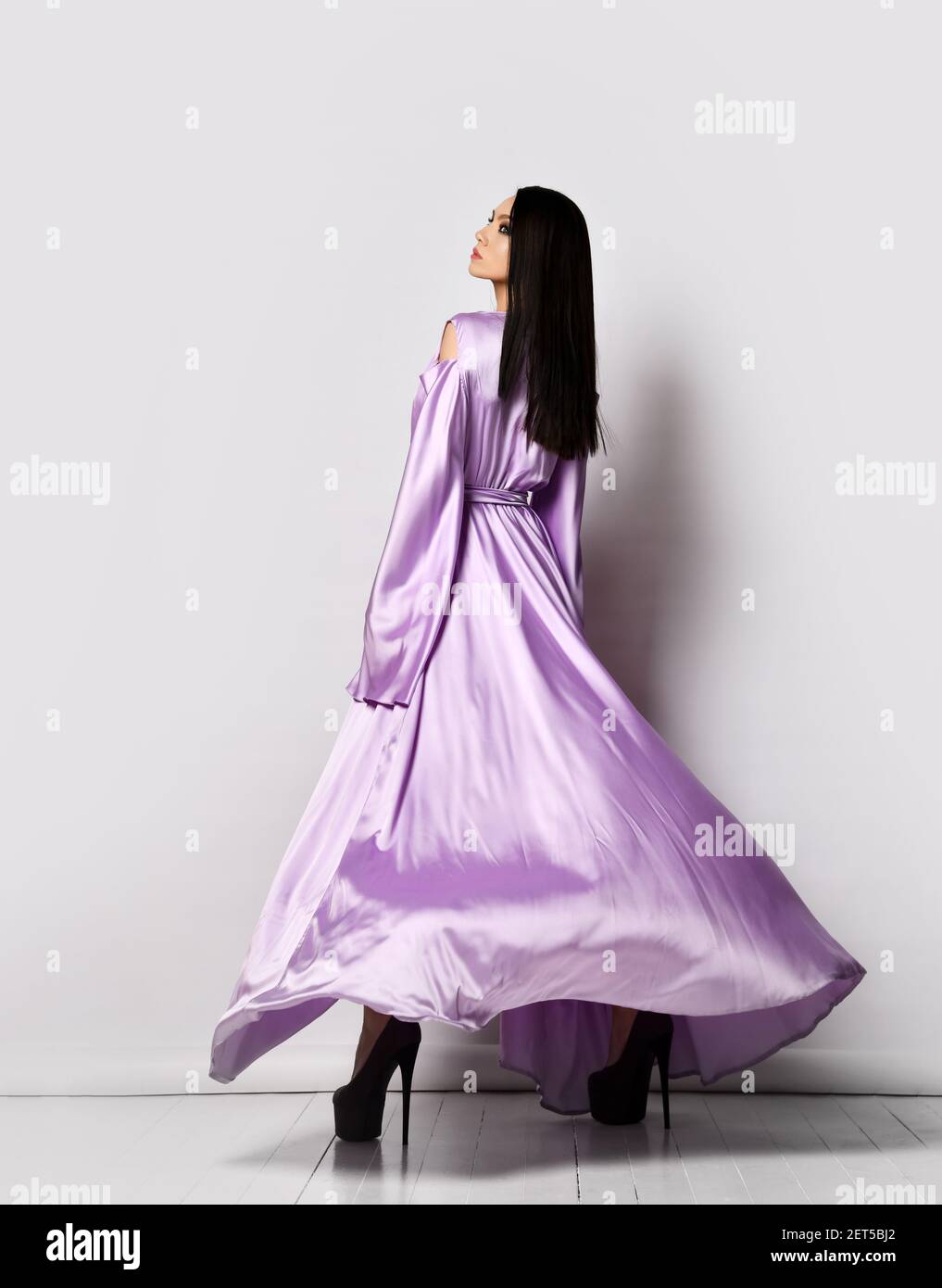 Young pretty woman in purple silky flying maxi dress and shoes standing ...