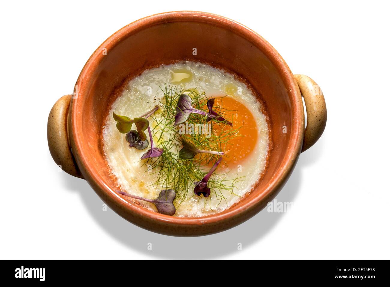 Ox-eye egg cooked and served in a clay pot with sprouts. Top view ...