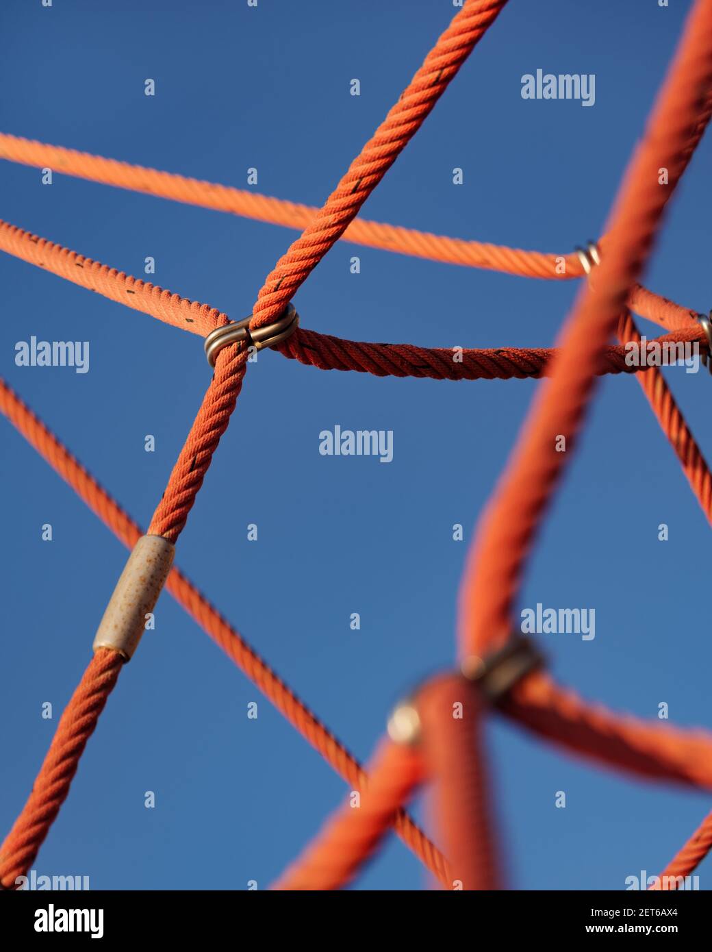 Abstract detail picture of climbing frame with red ropes and blue sky ...