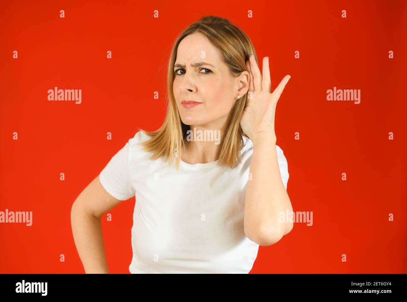 Young woman over isolated red background listening to something by ...