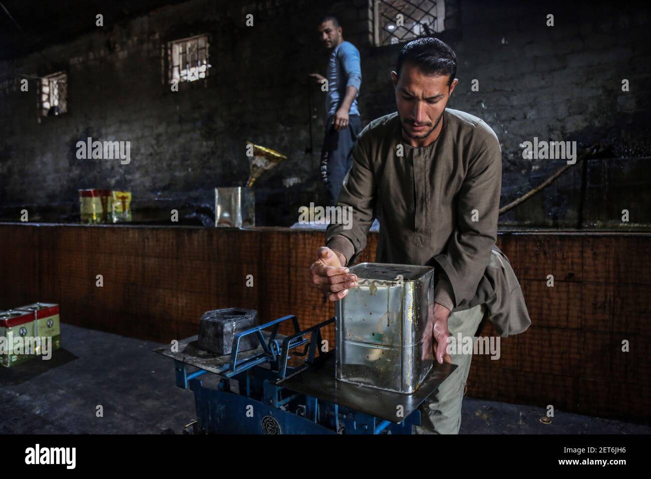 Mallawi, Egypt. 01st Mar, 2021. A worker weighs a can of freshly made ...