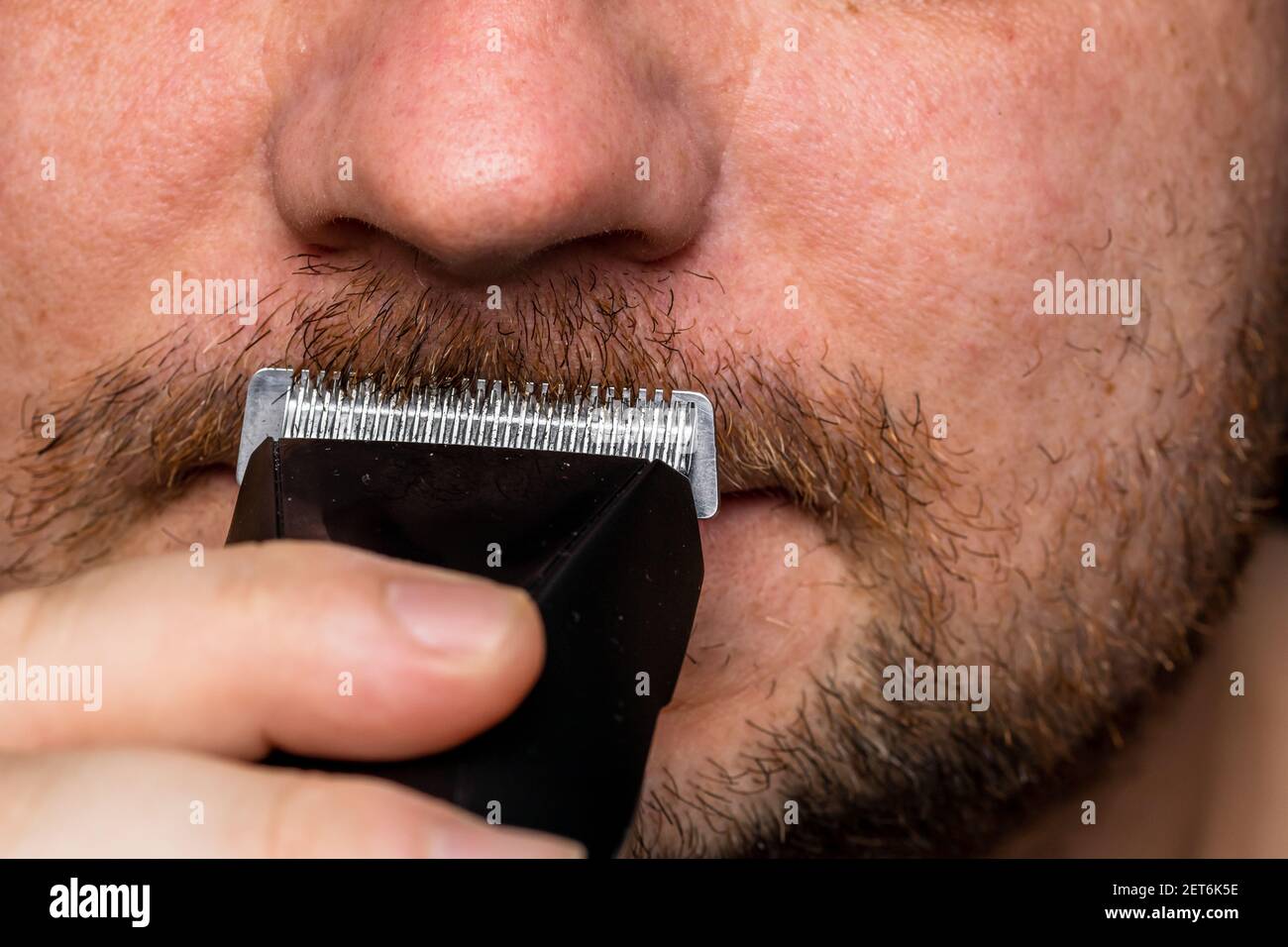 Man shaving or trimming his beard using a hair clipper Stock Photo - Alamy