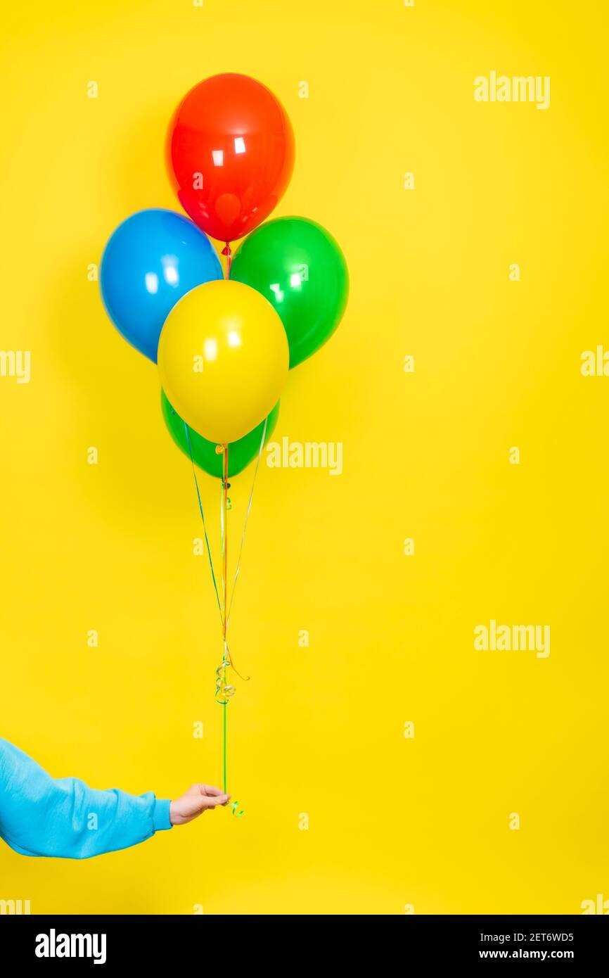 Female hand hold a bunch of colorful balloons. Party or present concept ...