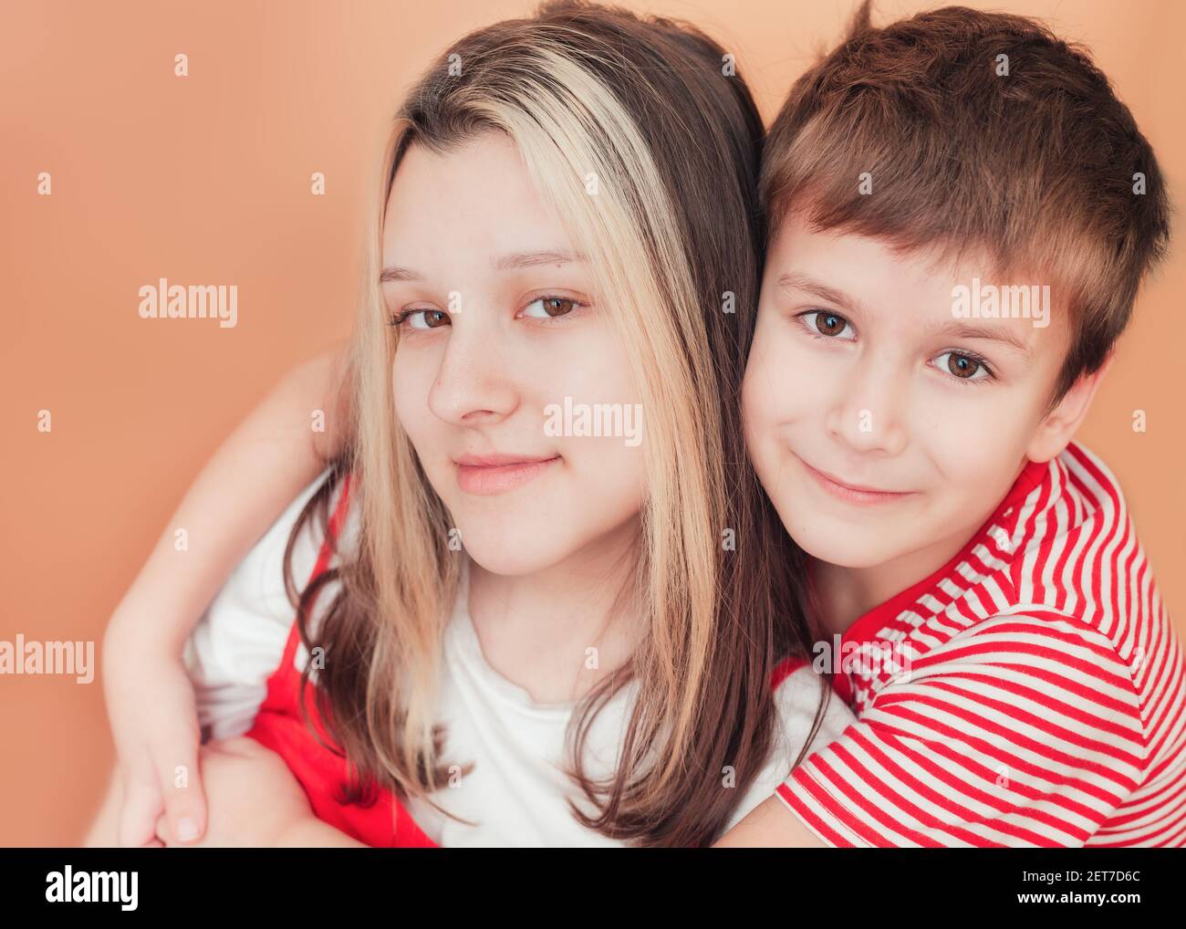 Portrait of children on brown background. Younger brother hugs his ...