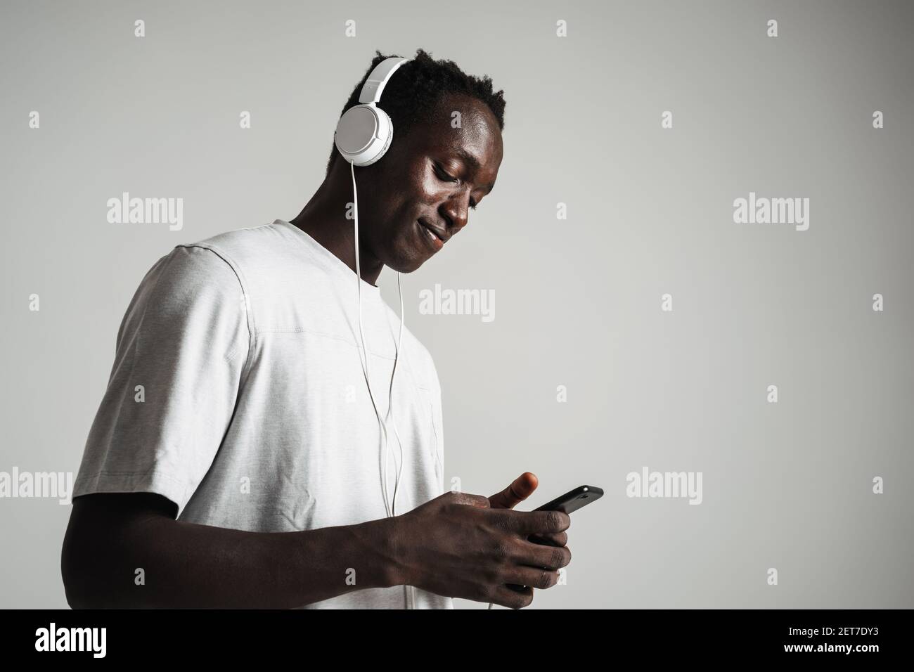 Happy young african man wearing casual outfit listening to music with ...