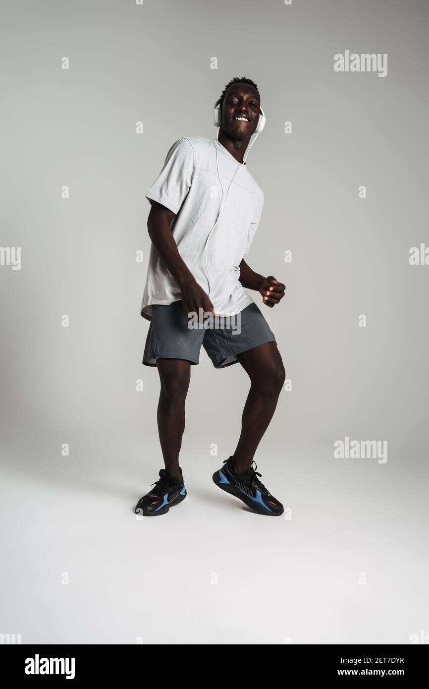 Happy young african man wearing casual outfit listening to music with ...