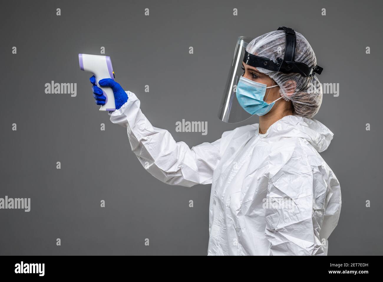 Young woman in a protective suit and blue gloves with an infrared ...