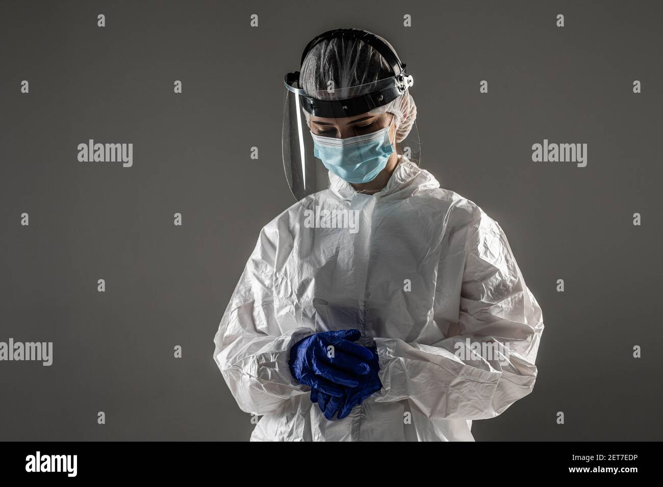 Female doctor in PPE wearing safety glasses gloves face mask and take ...