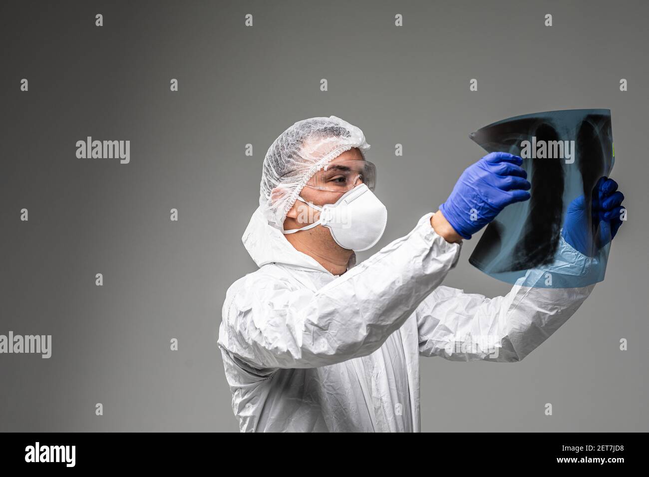 Medical staff in PPE suit hold chest x-ray film of patient to analyze ...