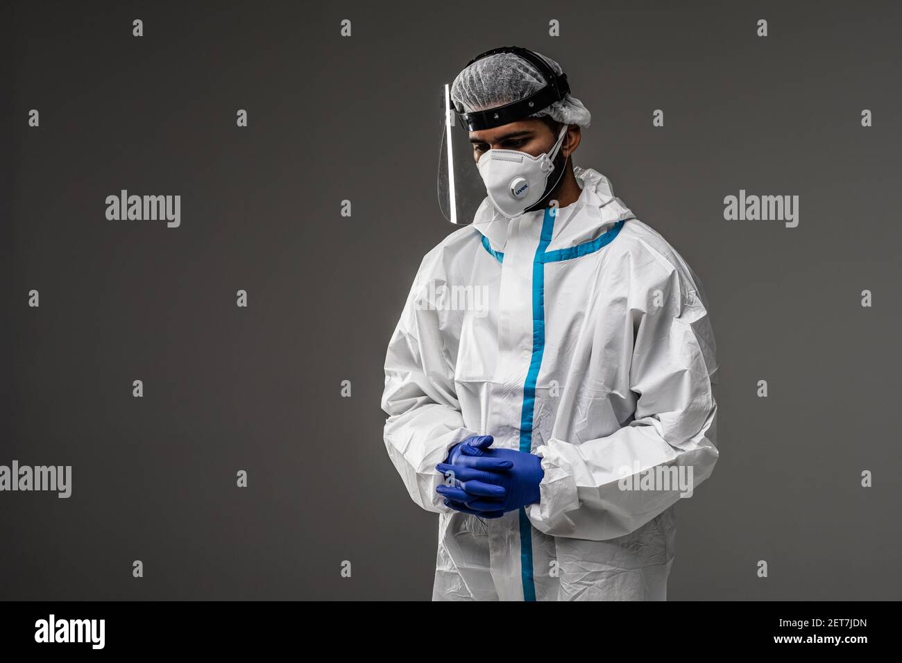 Tired man doctor wearing hazmat suit on grey background. Medical ...