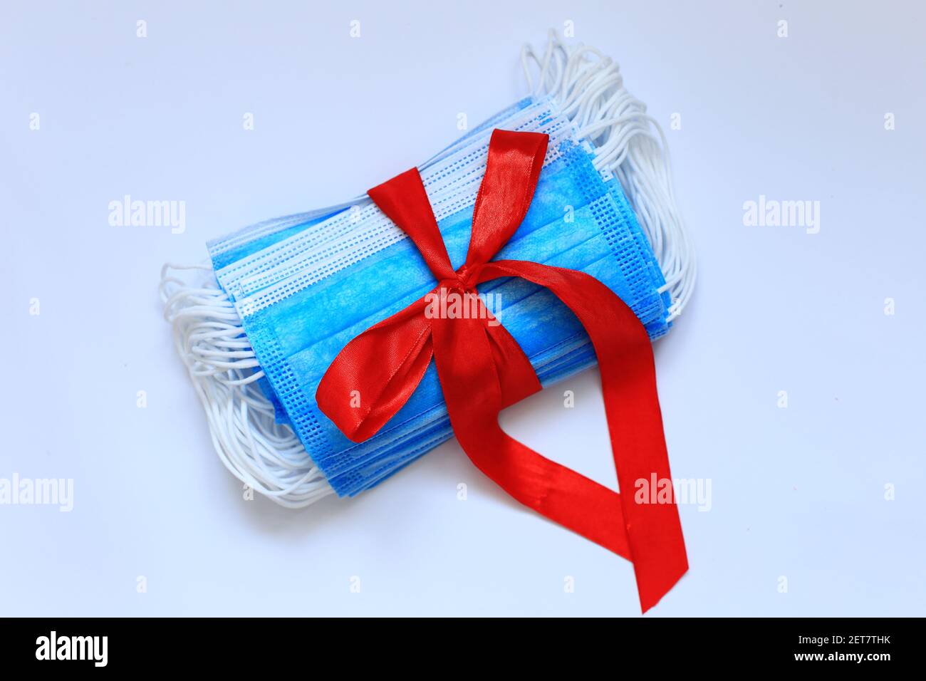 A lot of medical masks lie on a white background with a red ribbon ...