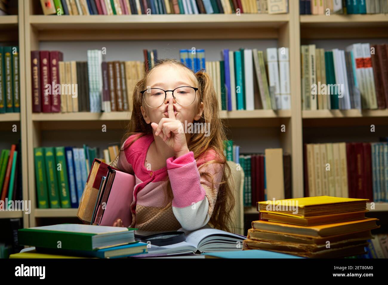 child girl asks to be quiet in library, school child sits alone at ...