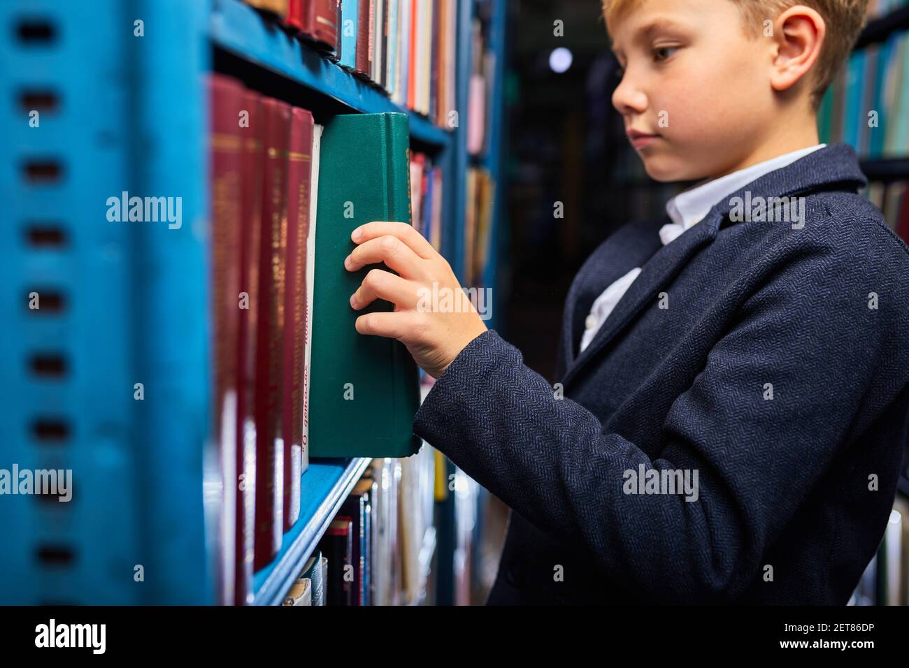 boy in school wear pulls out one book he wants to take from the library ...