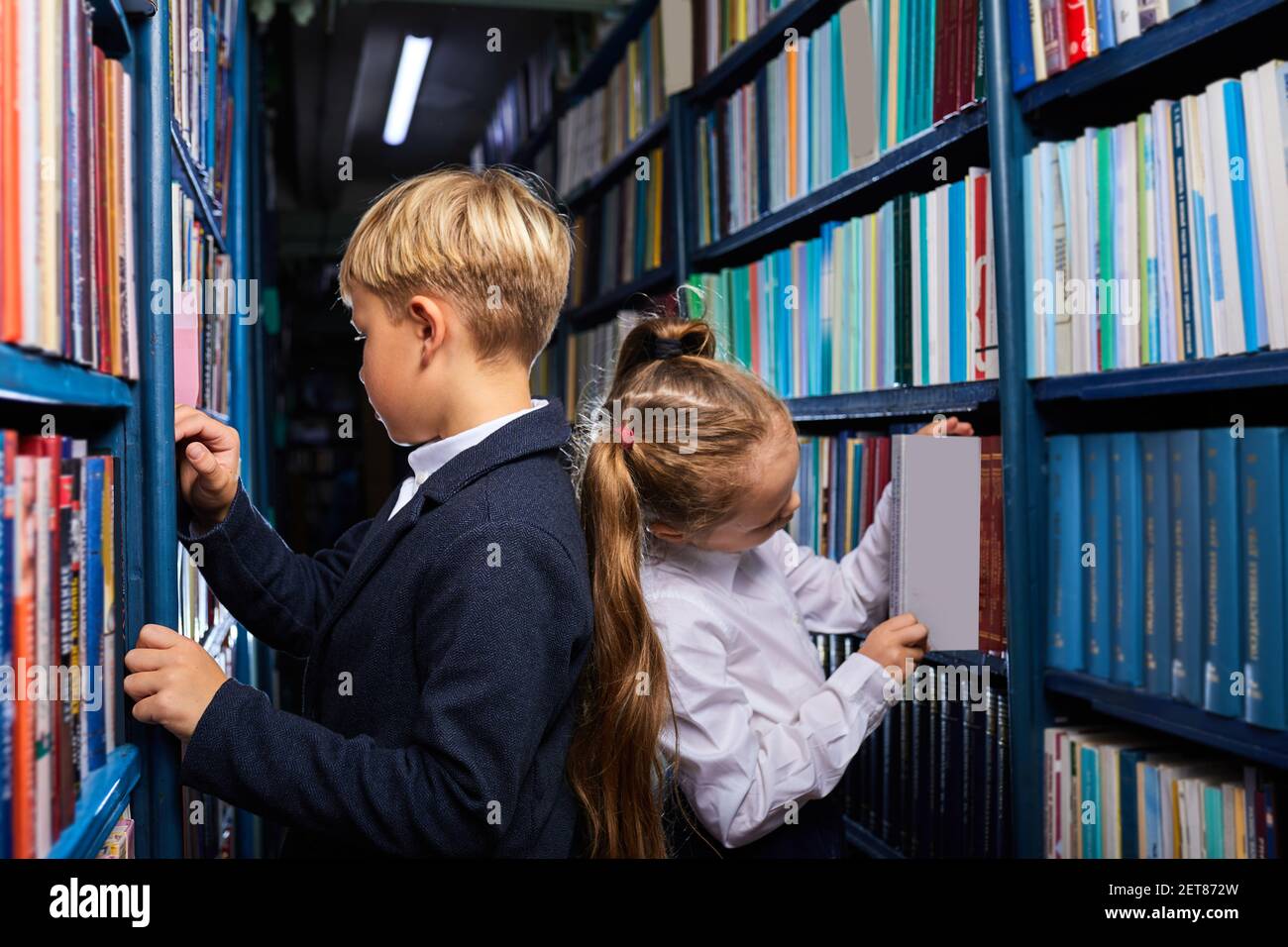school children in library choosing books standing between shelves back ...