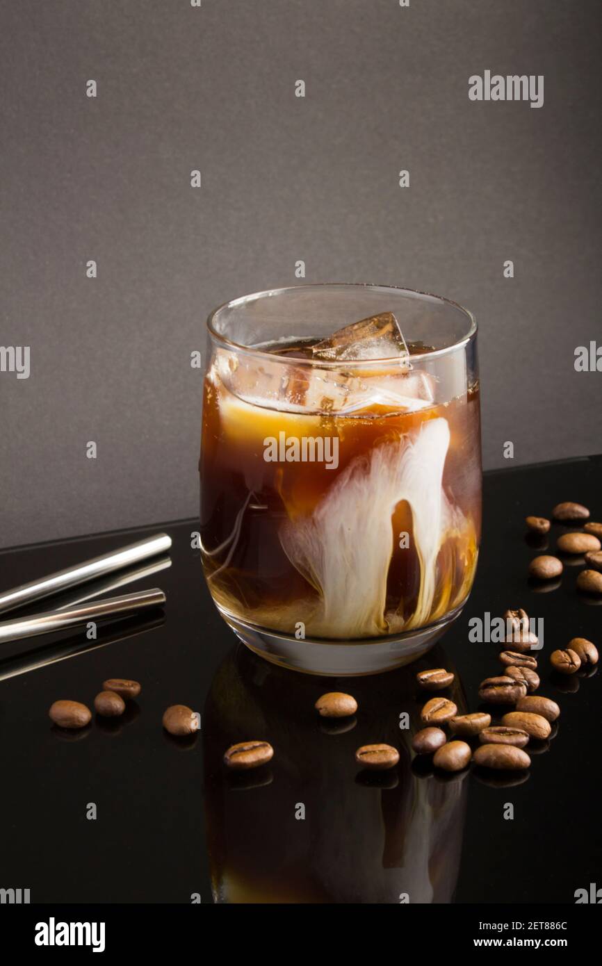 Cold brew coffee with milk in the glass drinking on the black ...