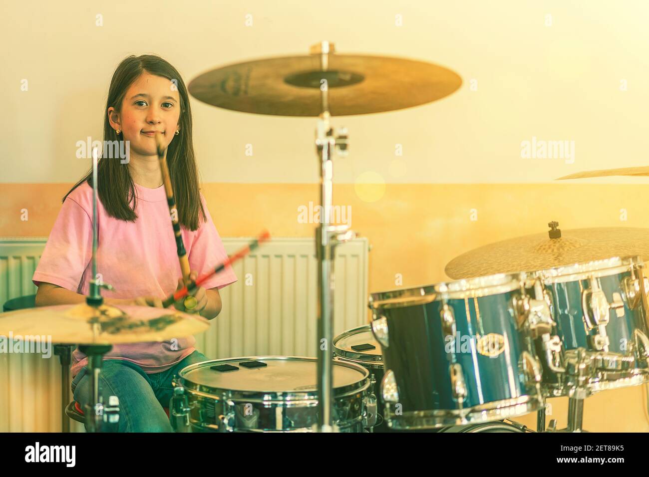 Happy girl in music therapy by playing drum kit on music room ...