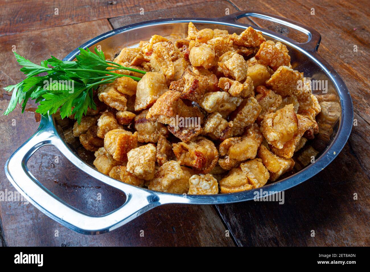 pork rinds (torresmo) on rustic wooden table in restaurant. typical ...